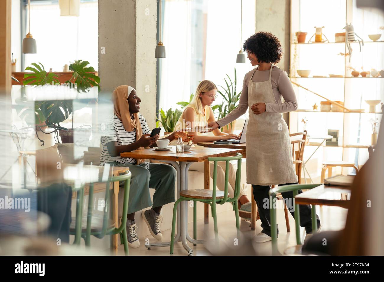 Smiling waitress serving food to customers in cafe Stock Photo - Alamy