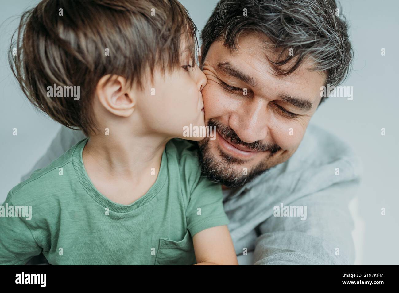 Son kissing father on cheek against white background Stock Photo - Alamy