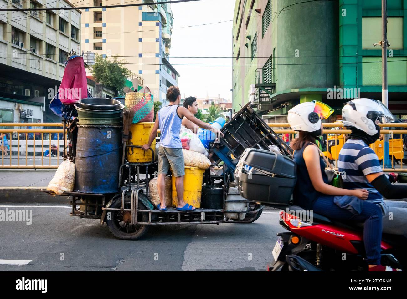 Some Filipino workers make a delivery of goods on a strange tractor ...