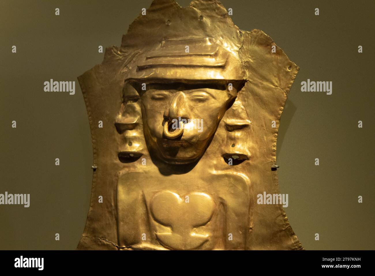 Closeup to a chaman figure with a nose ring into a golden pectoral ...