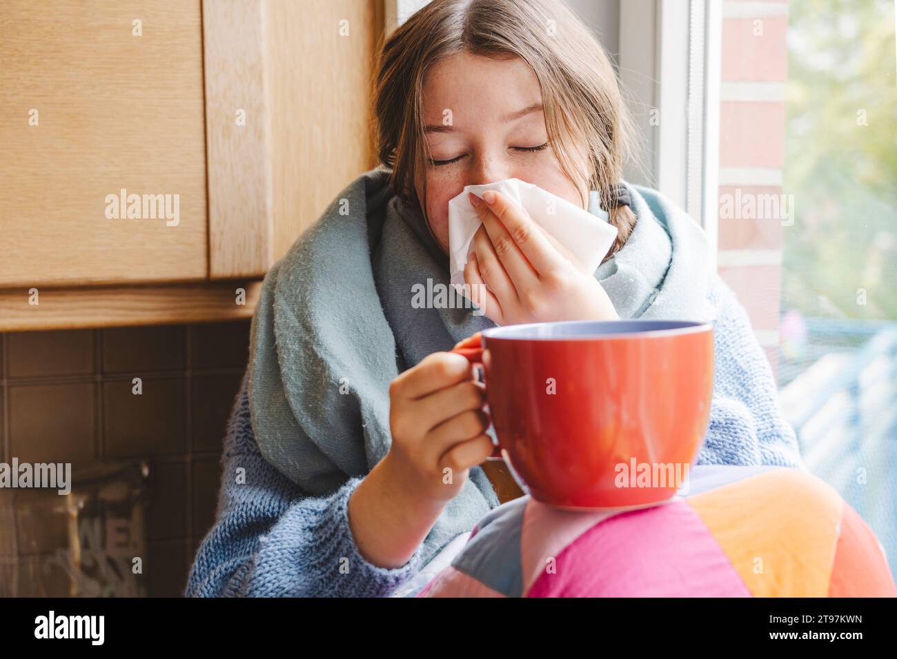 Teenage girl holding big coffee cup and cleaning nose with tissue at ...