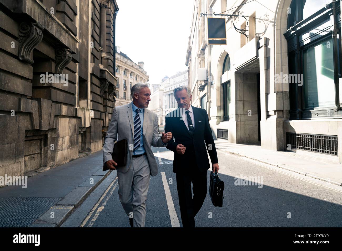 Businessmen walking and having discussion together on road Stock Photo ...