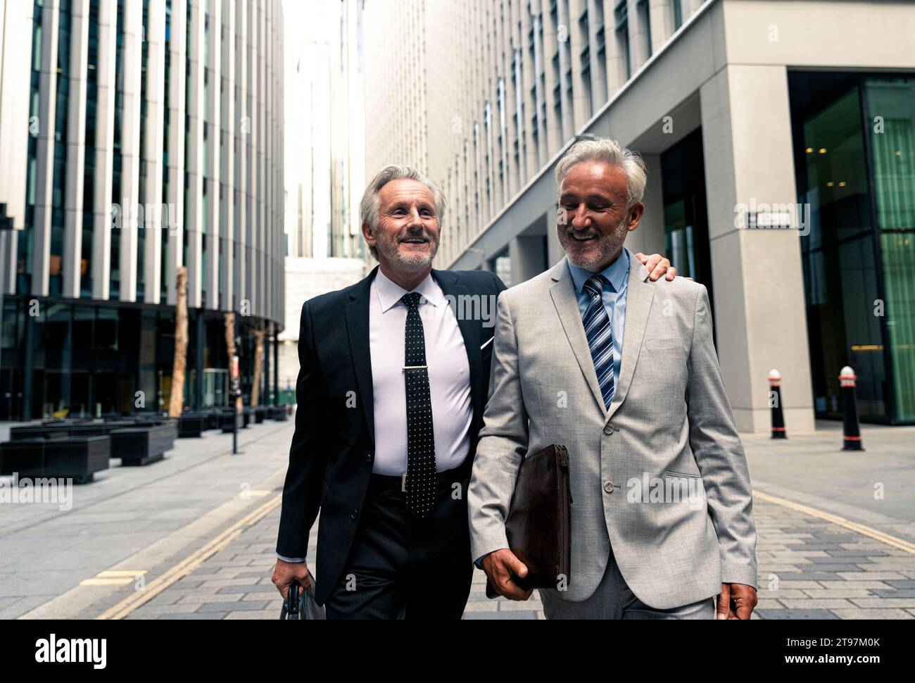 Happy senior businessmen walking and talking with each other amidst ...