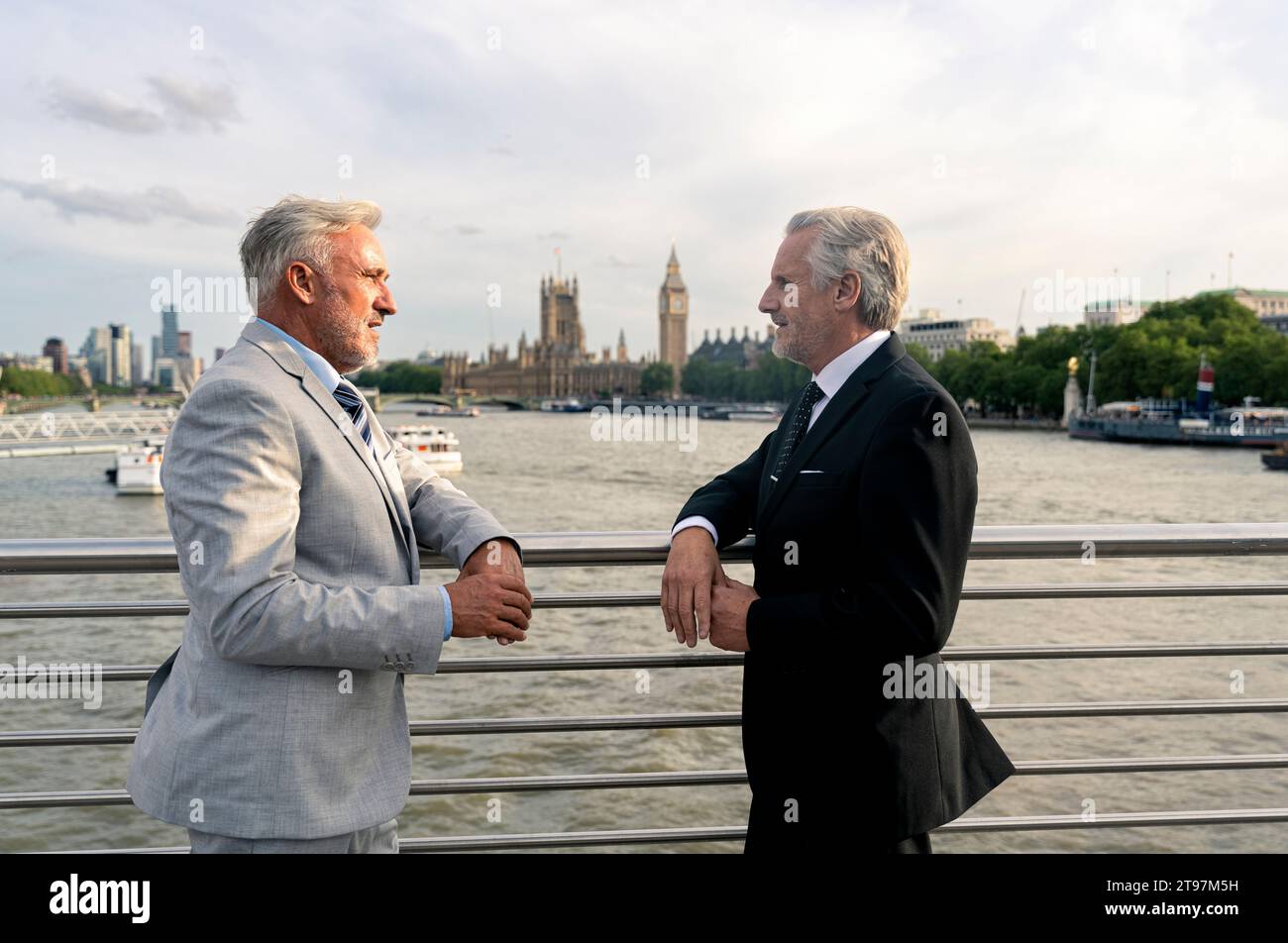 Senior businessmen talking near river on bridge in London city Stock ...
