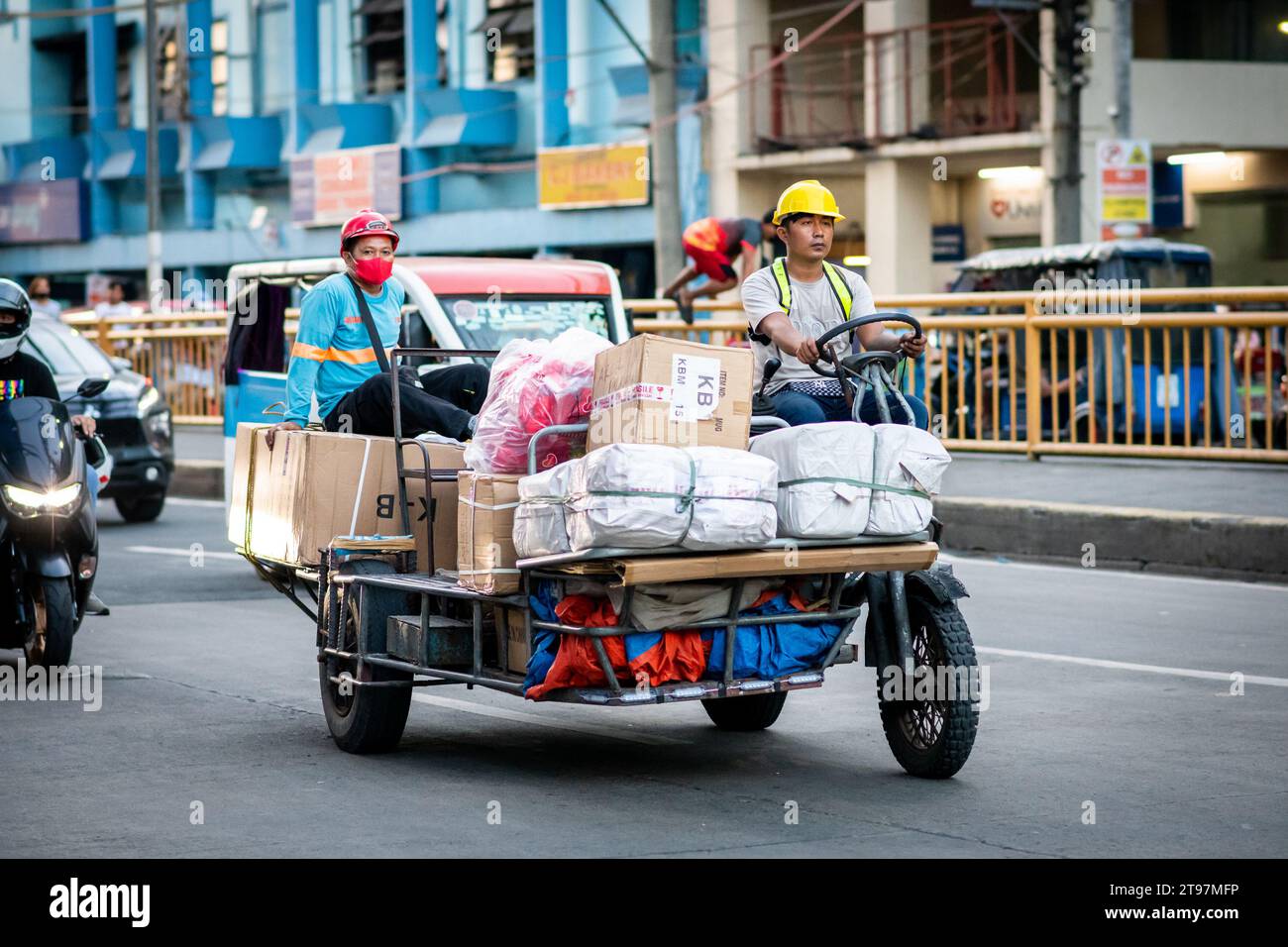 Some Filipino workers make a delivery of goods on a strange tractor ...