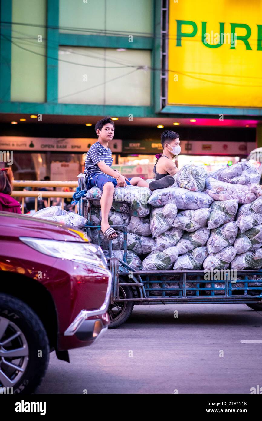 Some Filipino workers make a delivery of goods on a strange tractor ...