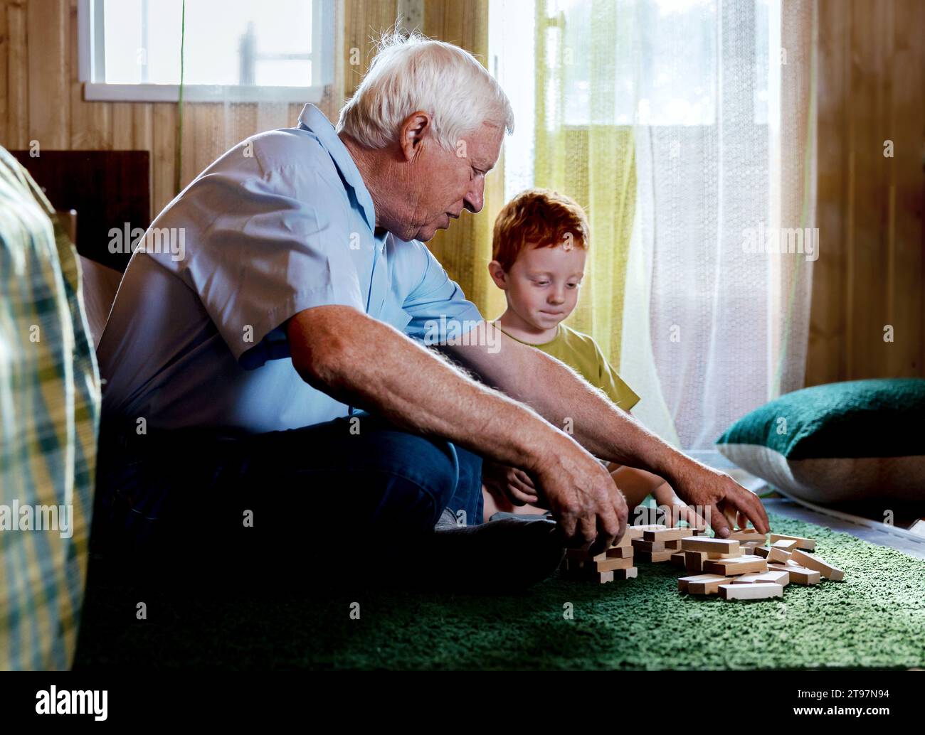 Senior man and grandson playing block removal game at home Stock Photo ...