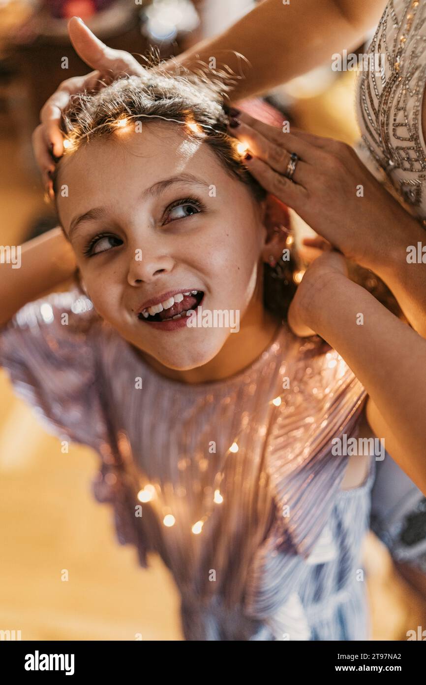 Woman adjusting string light on daughter's forehead at home Stock Photo ...
