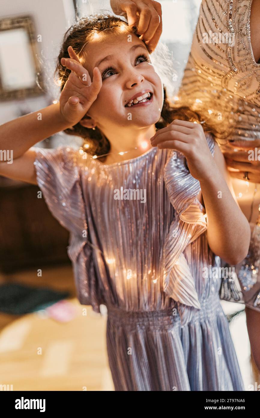 Mother adjusting string light on daughter's forehead at home Stock ...
