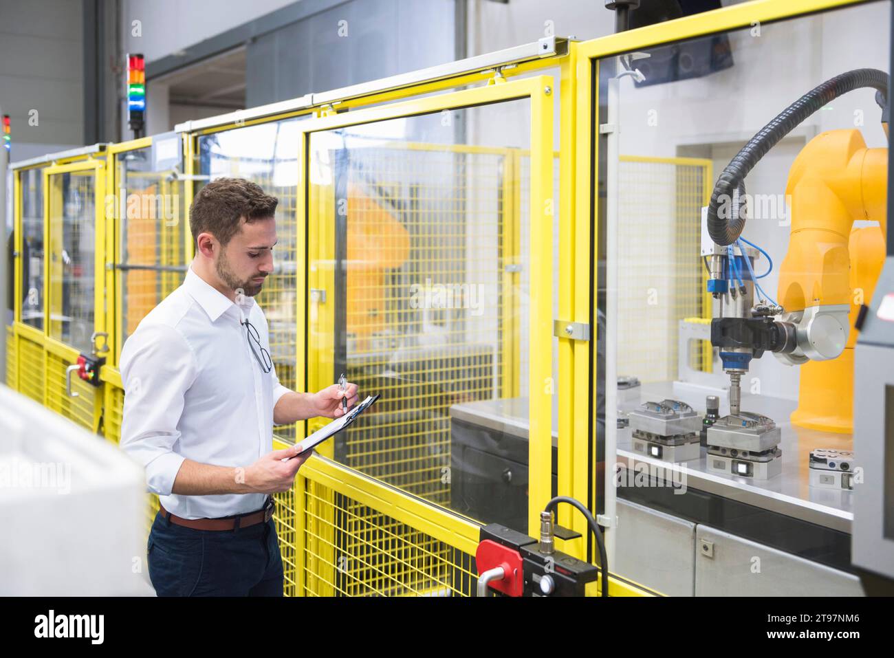 Engineer examining checklist near robotic arm at factory Stock Photo ...