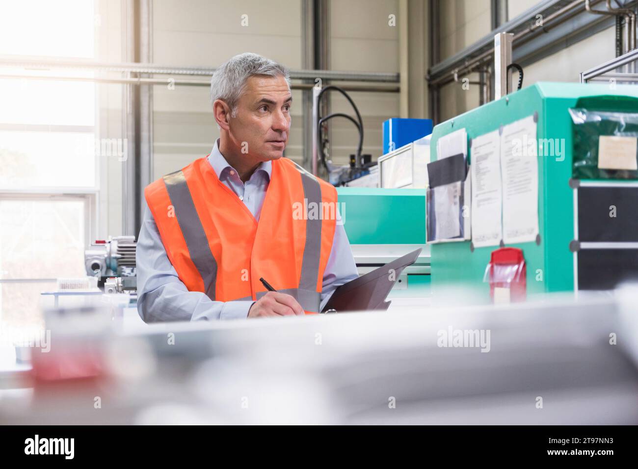 Engineer examining with file folder in factory Stock Photo - Alamy