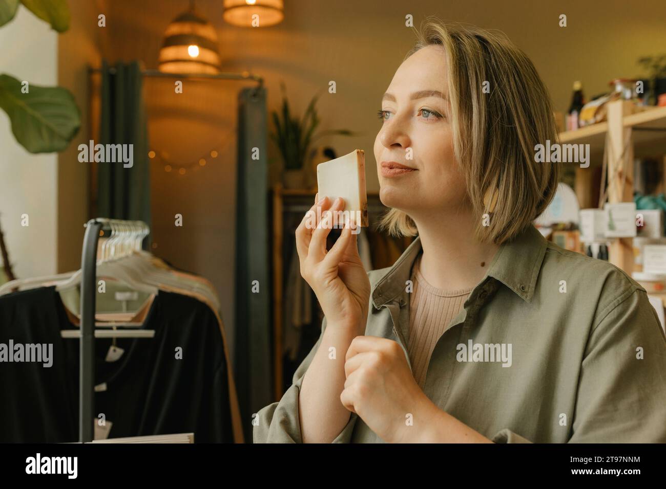 Thoughtful blond woman smelling soap bar in retail store Stock Photo ...