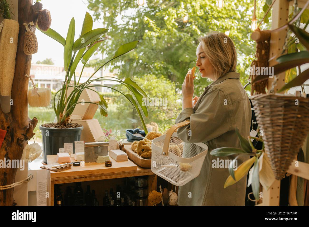 Woman with shopping basket smelling bar of soap in retail store Stock ...