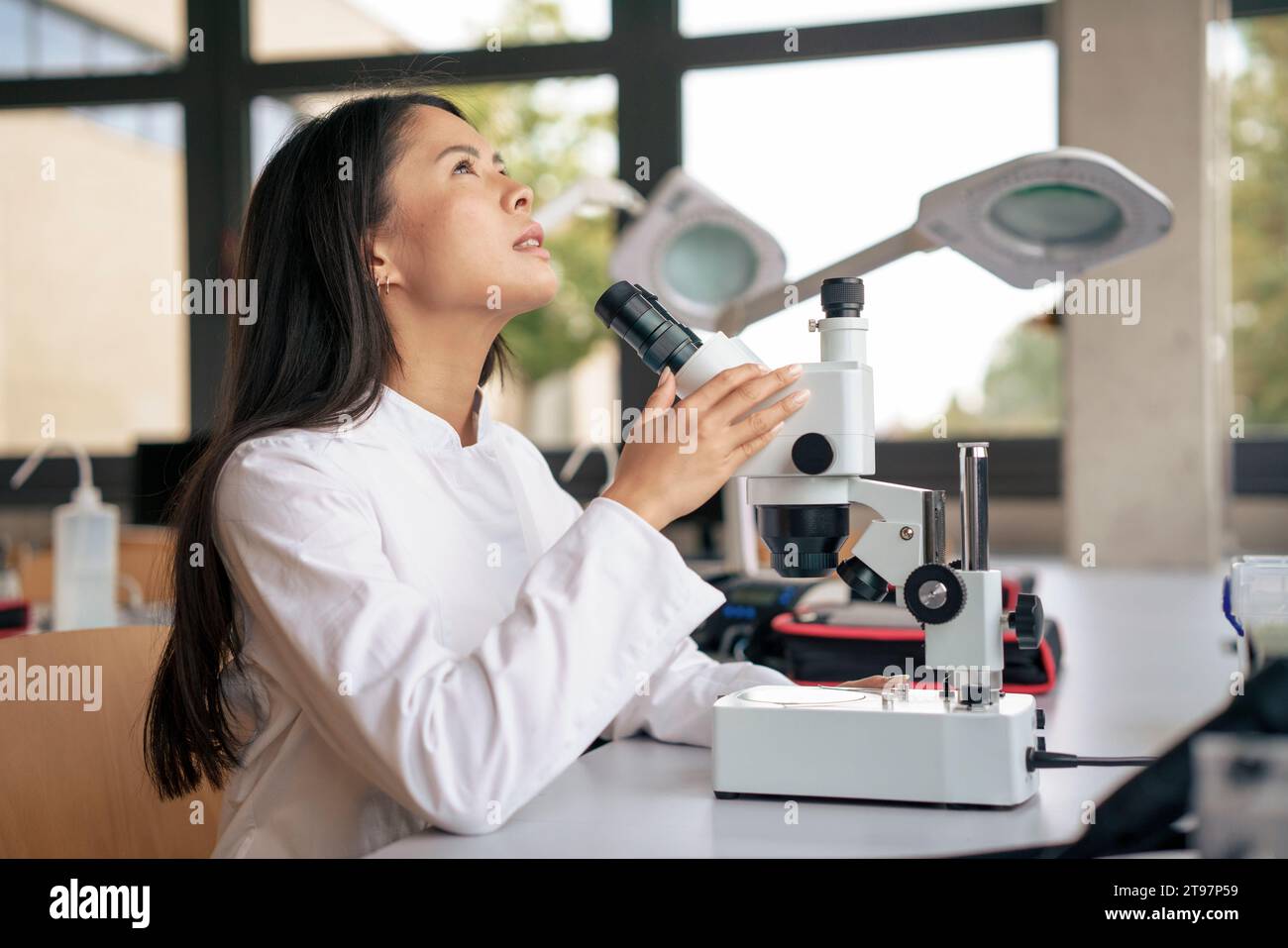 Thoughtful scientist sitting with microscope at desk Stock Photo - Alamy