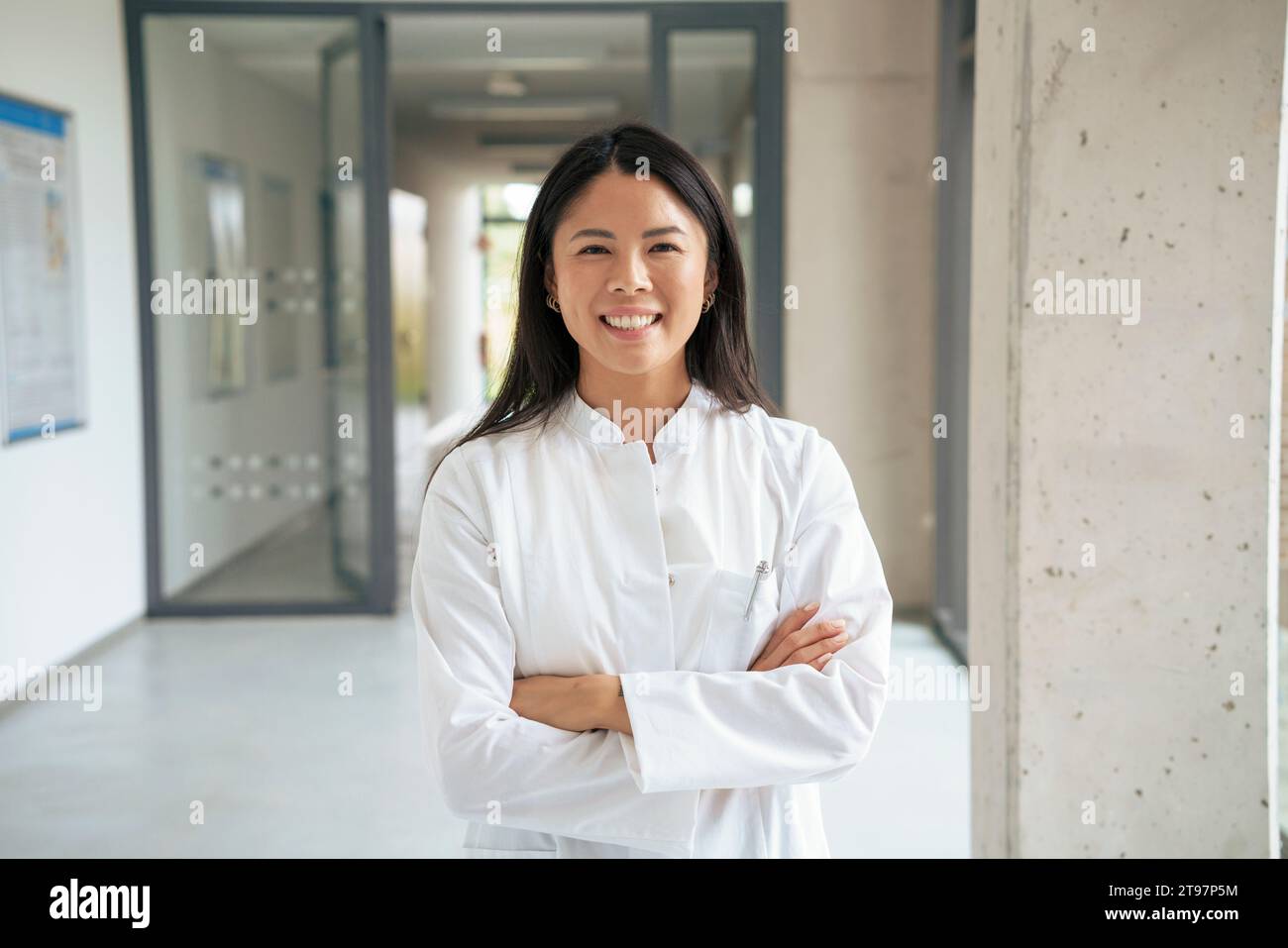 Happy scientist with arms crossed standing in corridor Stock Photo - Alamy