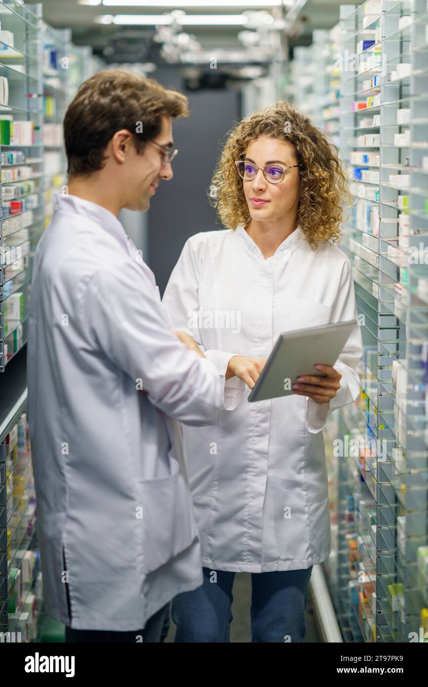Pharmacists having discussion of medical supply amidst medicine shelves ...