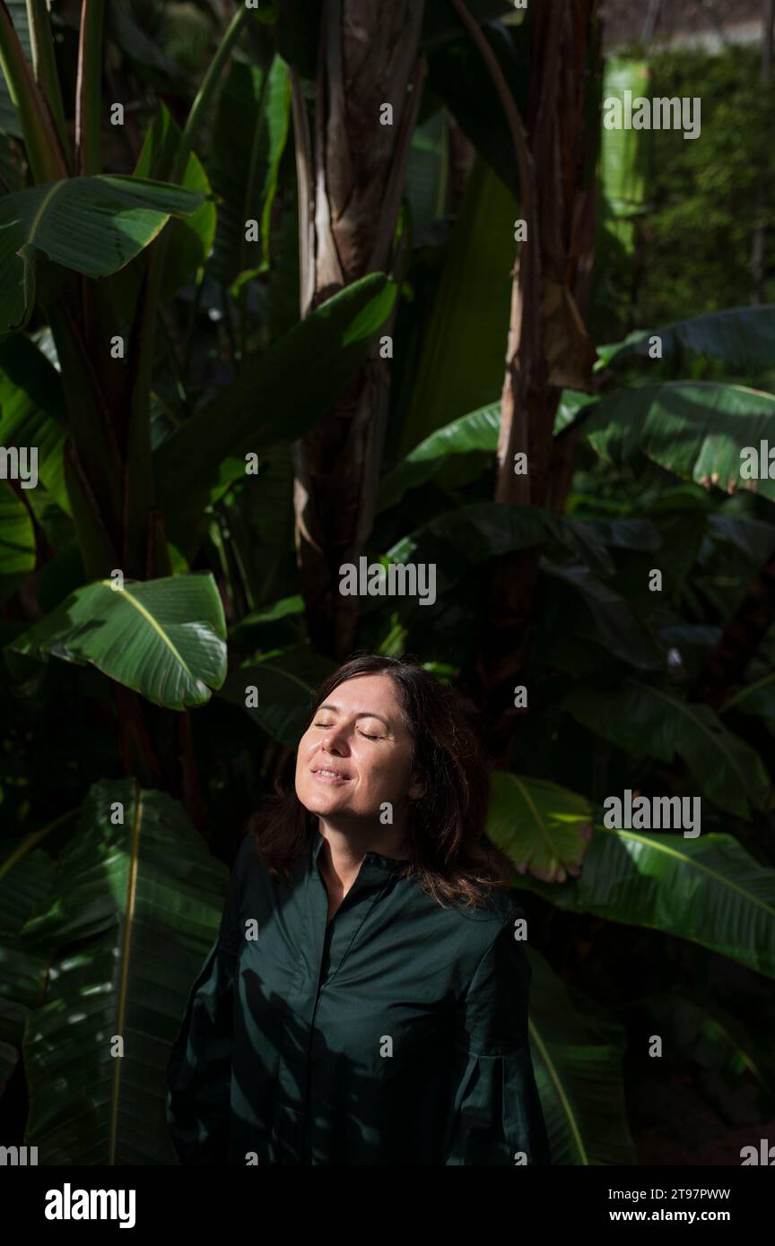 Mature woman with eyes closed in botanical garden Stock Photo - Alamy