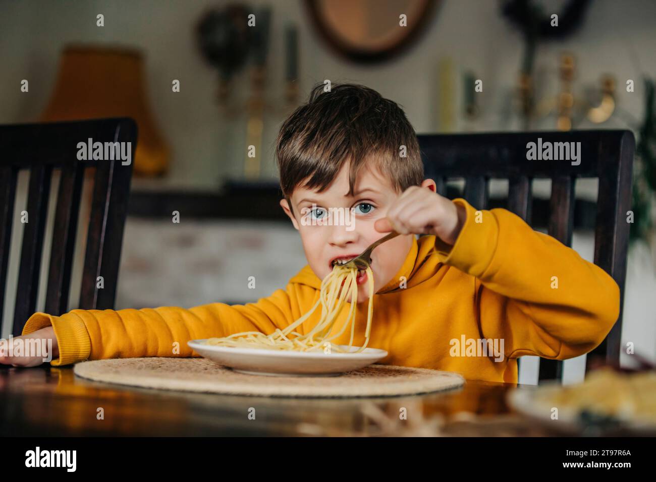 Boy wearing hooded shirt eating pasta at home Stock Photo - Alamy
