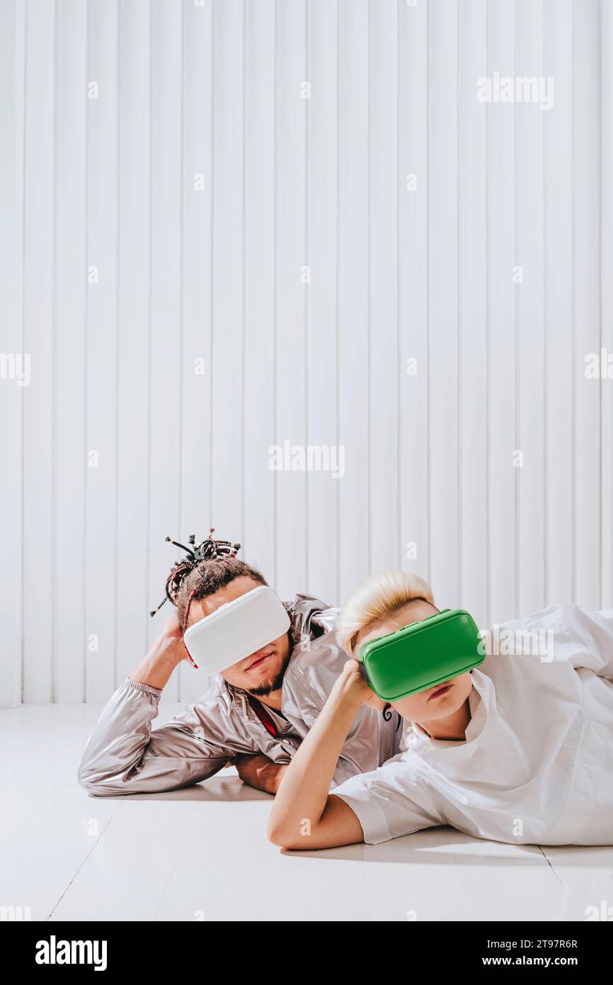 Young man and woman wearing virtual reality headset lying on side in ...