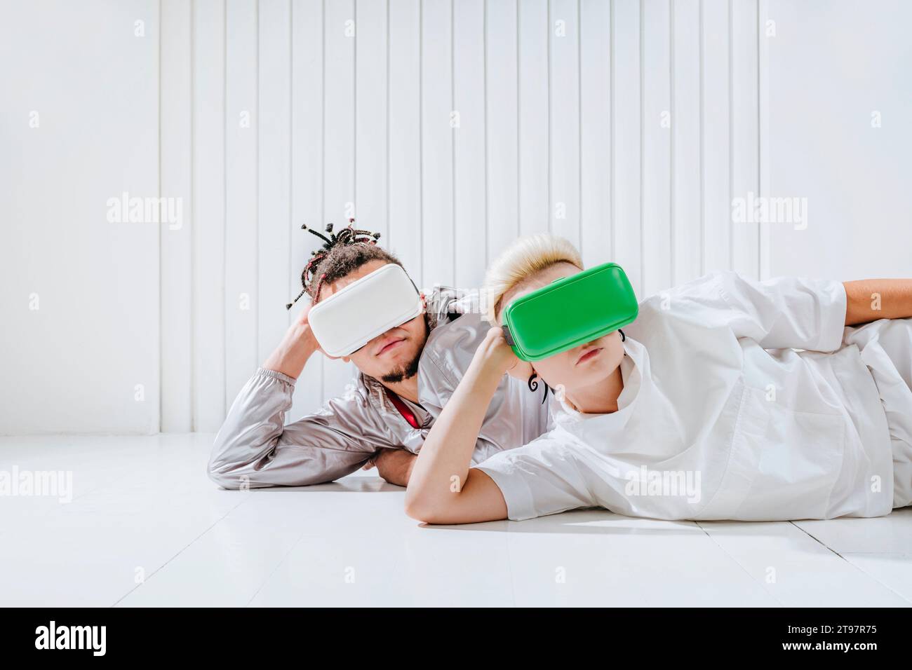 Man and woman wearing virtual reality headset lying on side in front of ...