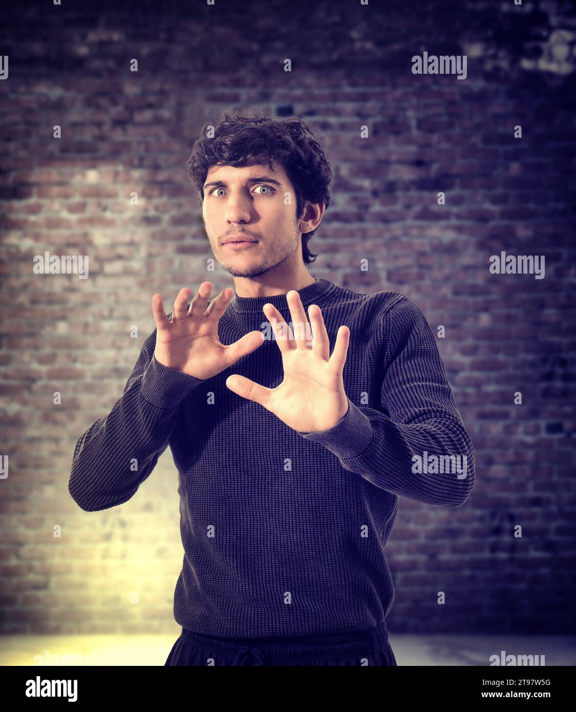A man standing in front of a brick wall making a stop sign Stock Photo ...