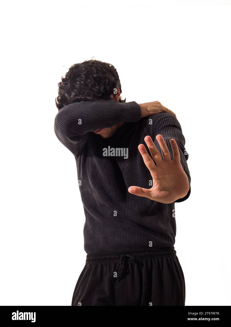 A scared man in a black sweater is protecting himself with one arm and ...