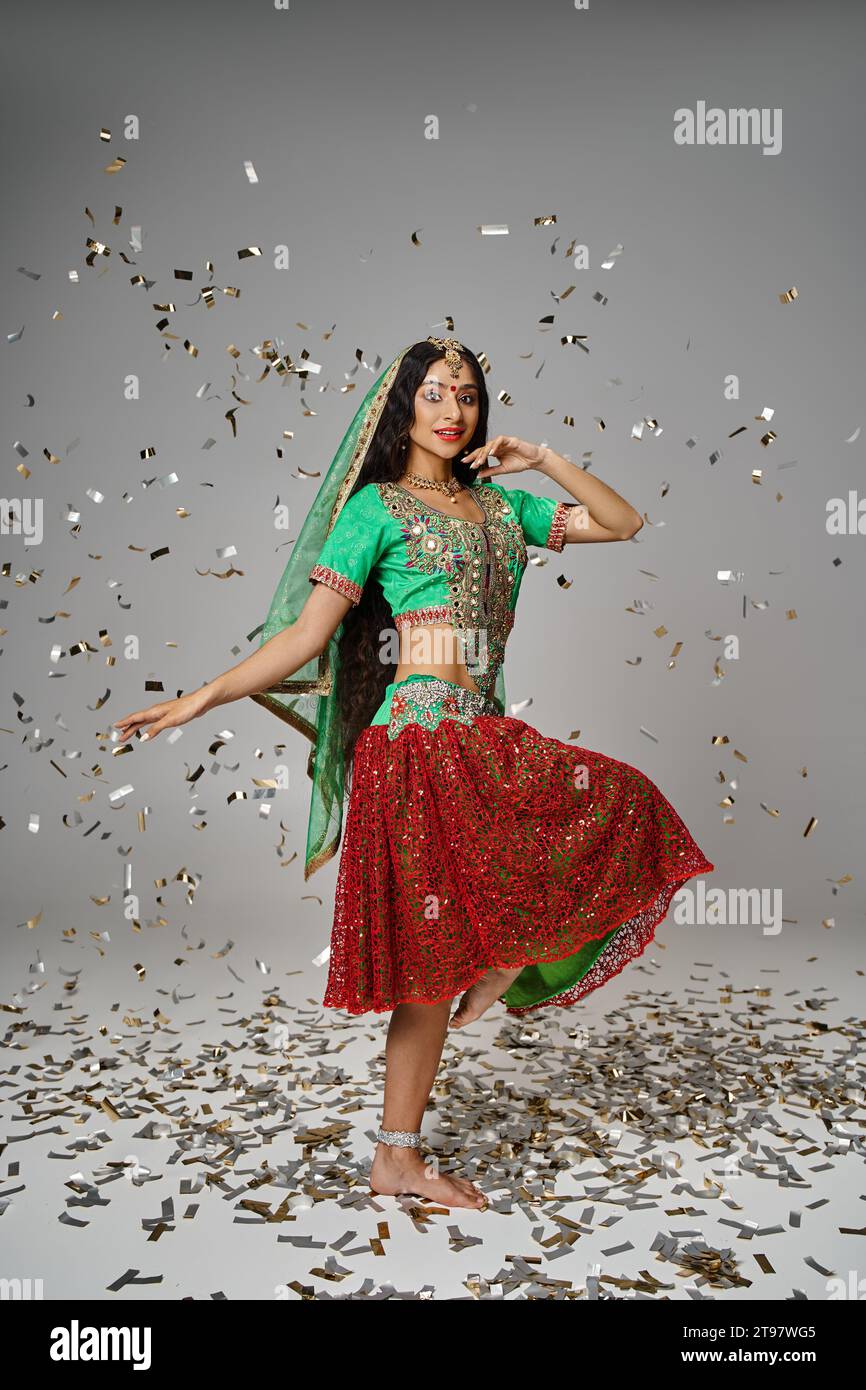 vertical shot of young indian woman with bindi standing on one leg and ...