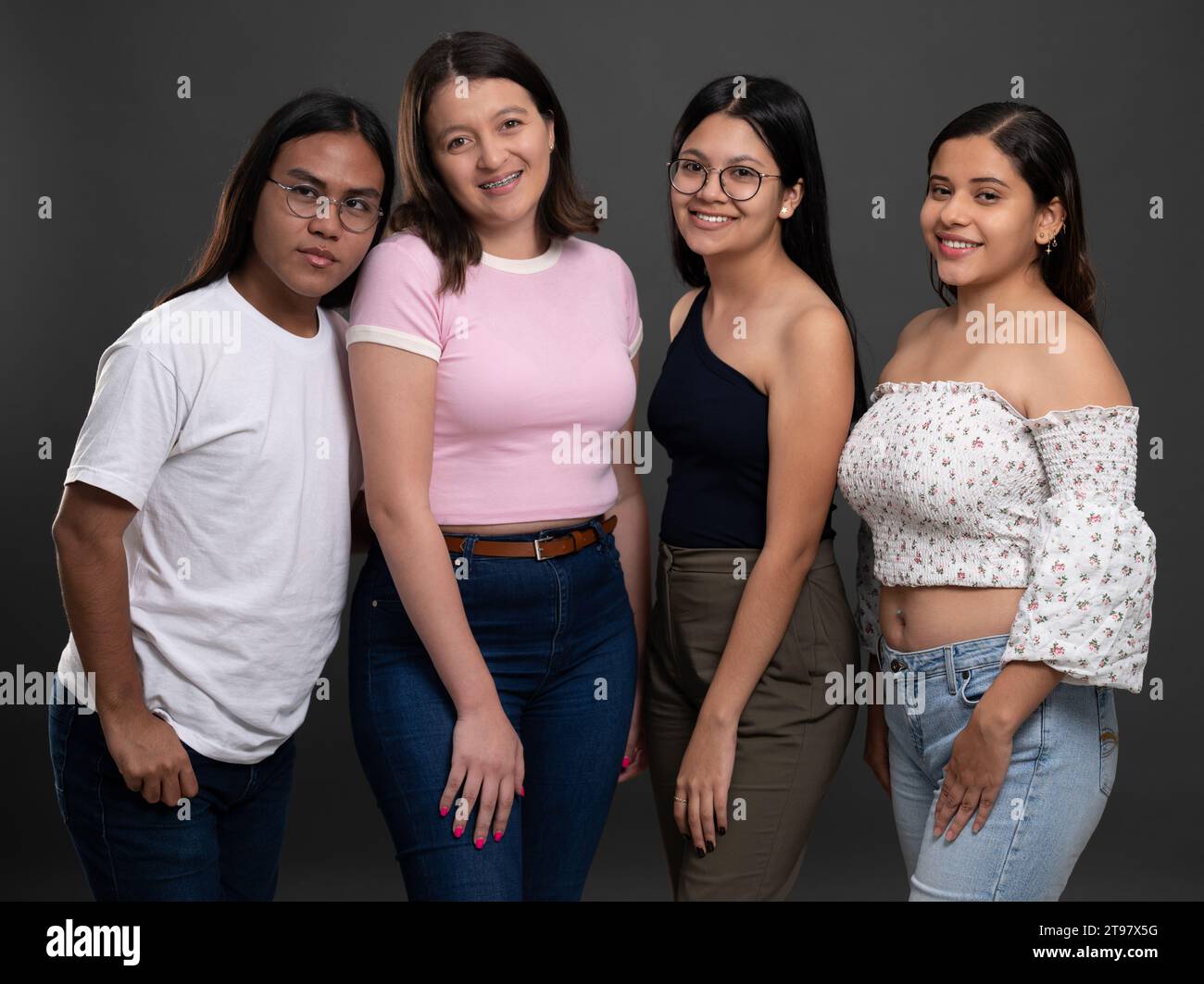 Four smiling latin american young people on grey studio background ...