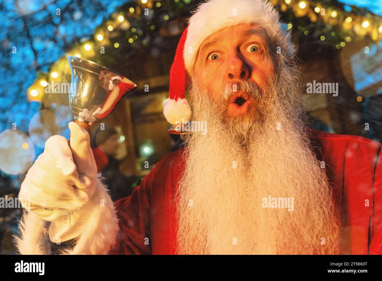 Santa Claus with surprised look, ringing a bell at a Christmas market ...