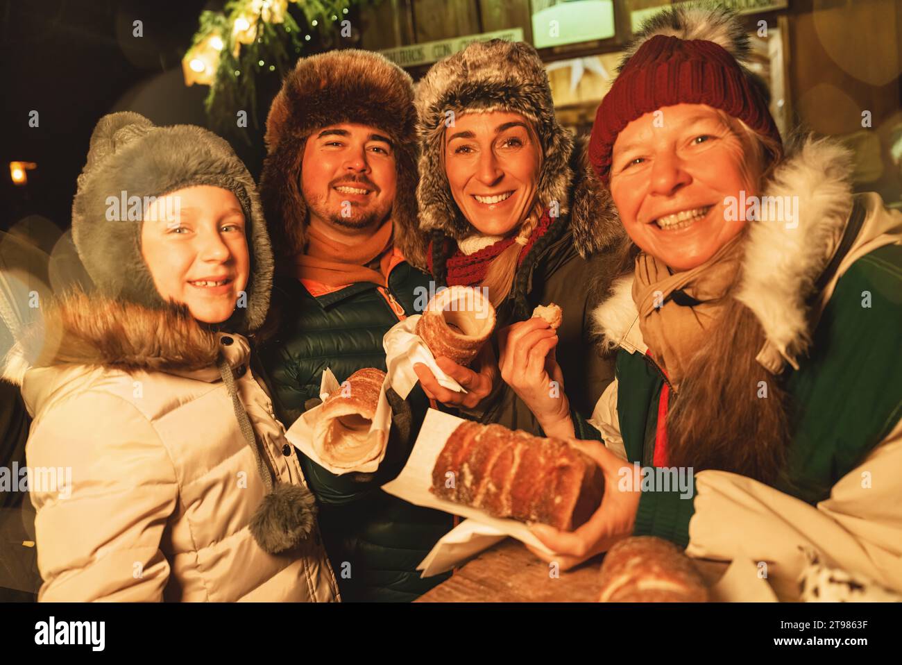 Happy family eating Baumstriezel or trdelnik in front of a Christmas ...