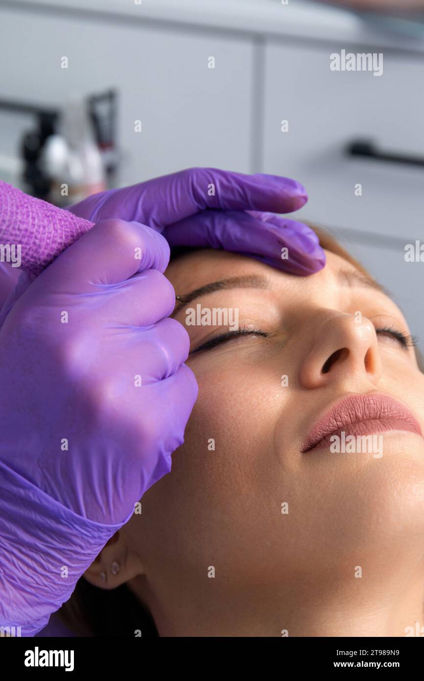 Beauty master performs permanent eyebrow makeup in a beauty salon ...
