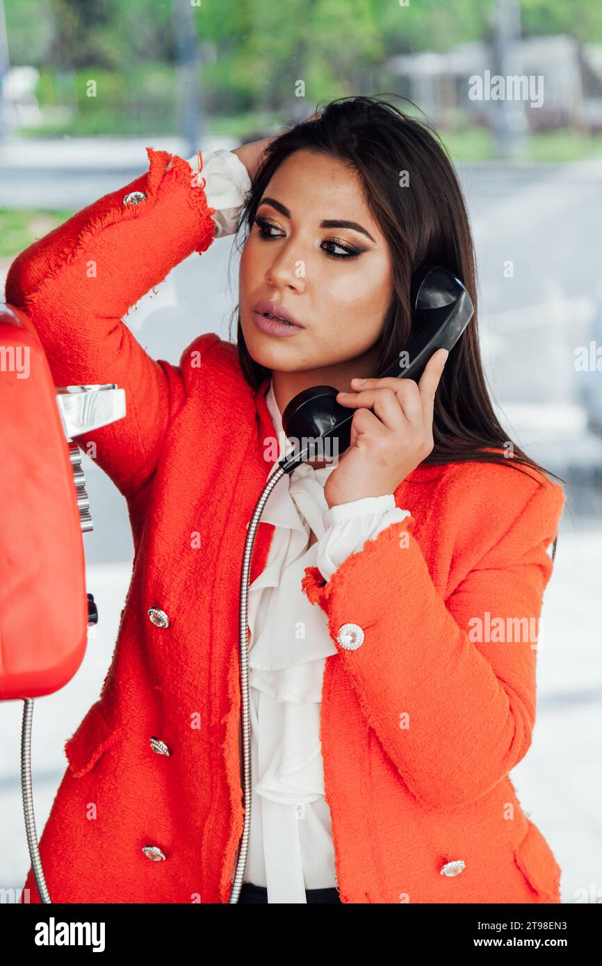 Beautiful woman in red business suit talking on city payphone Stock ...