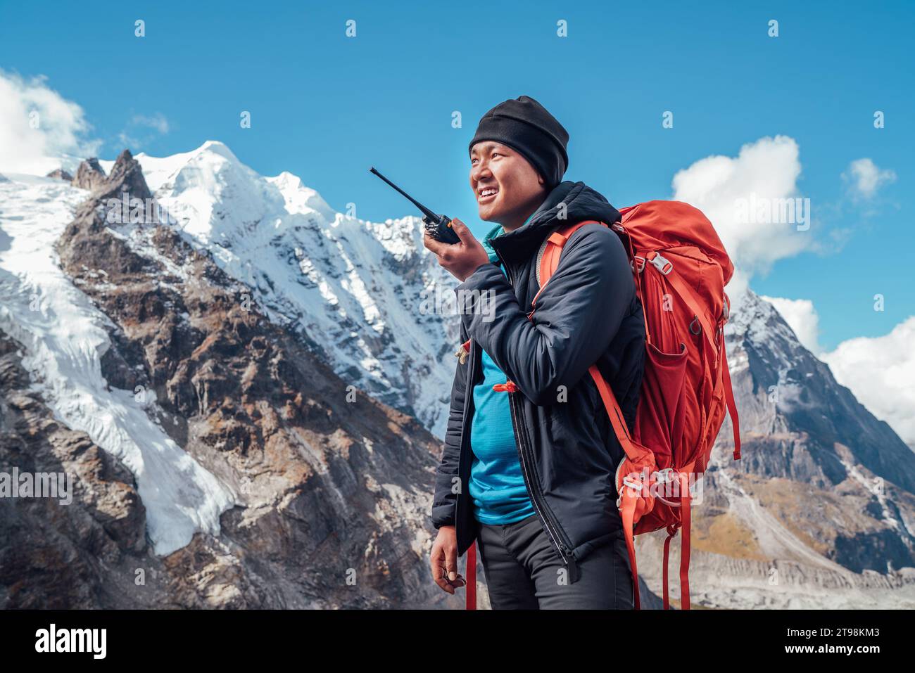 Portrait of Sherpa man with backpack using walkie-talkie for calling ...