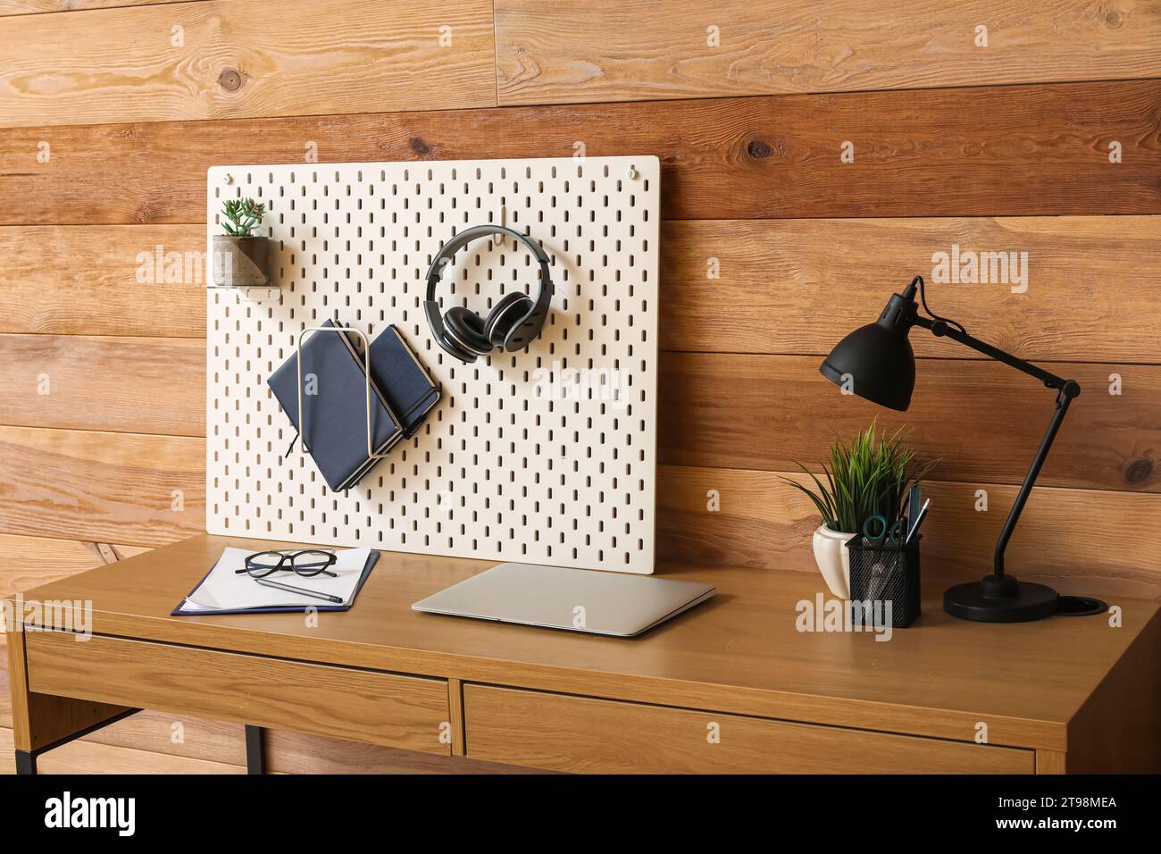 Modern workplace with pegboard near wooden wall in office Stock Photo ...