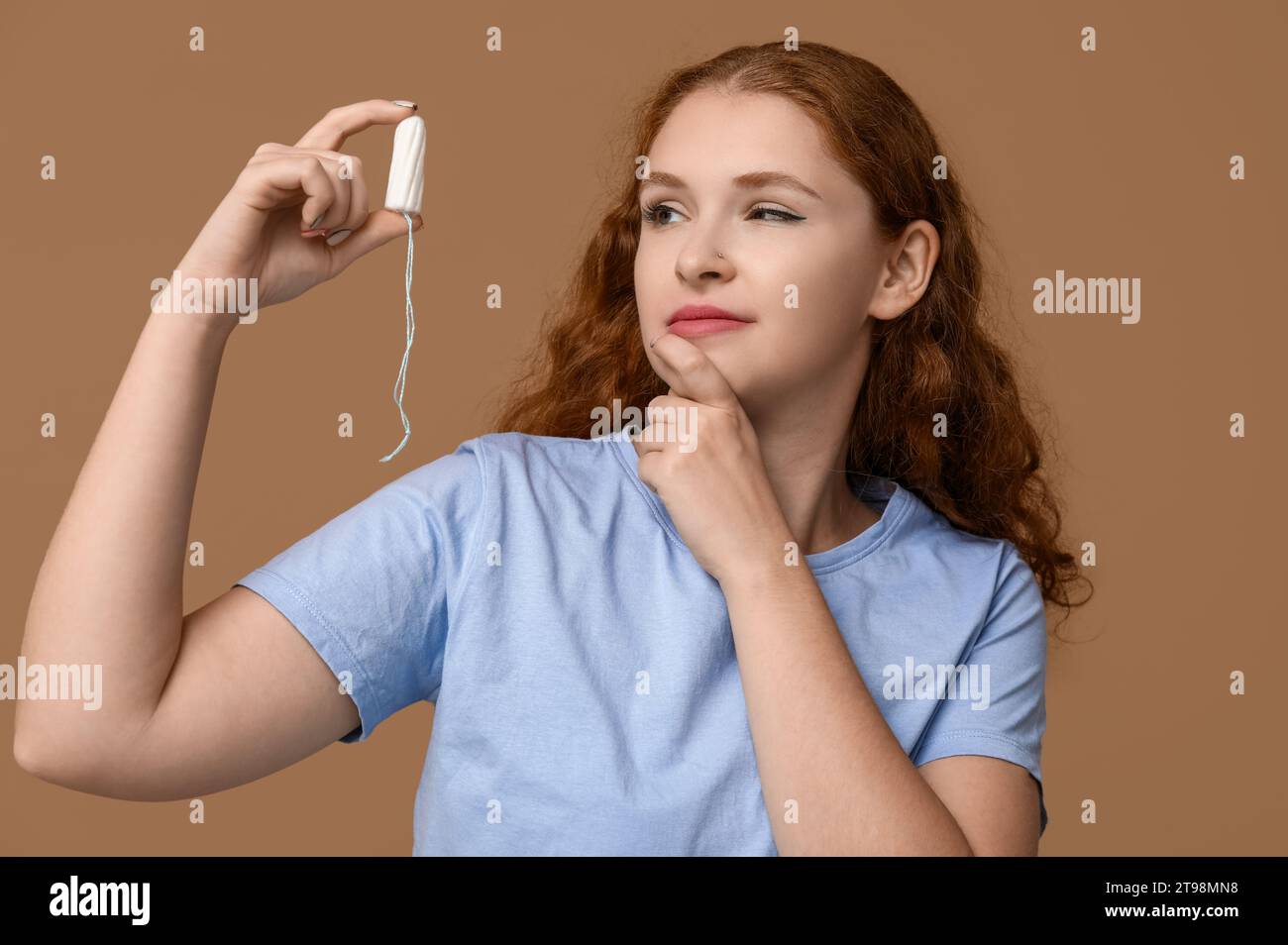 Beautiful young thoughtful woman with tampon on brown background Stock ...