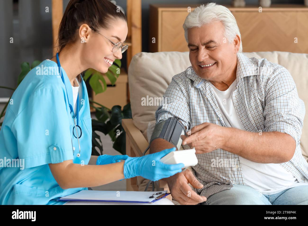 Female nurse measuring blood pressure of senior man at home Stock Photo ...