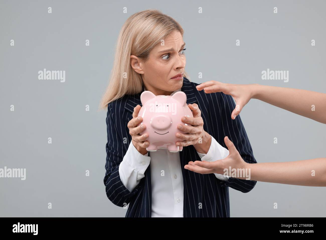 Scammer taking piggy bank from scared woman on grey background. Be ...