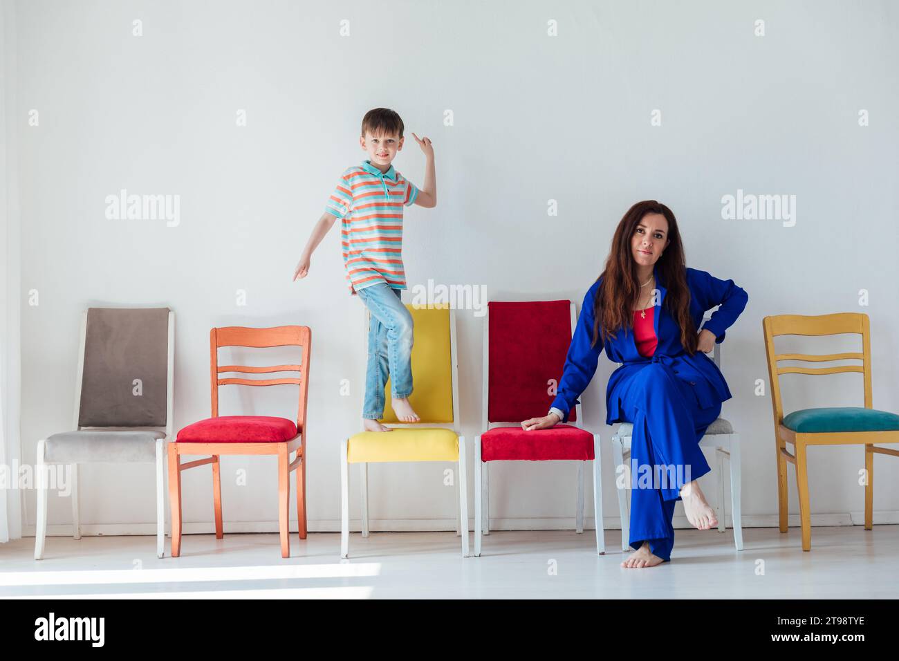 Boy and woman sitting on different chairs in white room interior Stock ...