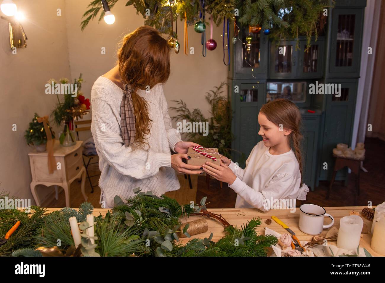 Daughter gives craft box with candy canes to mother workshop interior ...