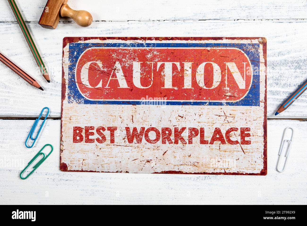 BEST WORKPLACE. Metal CAOTION plate with text on a white wooden ...