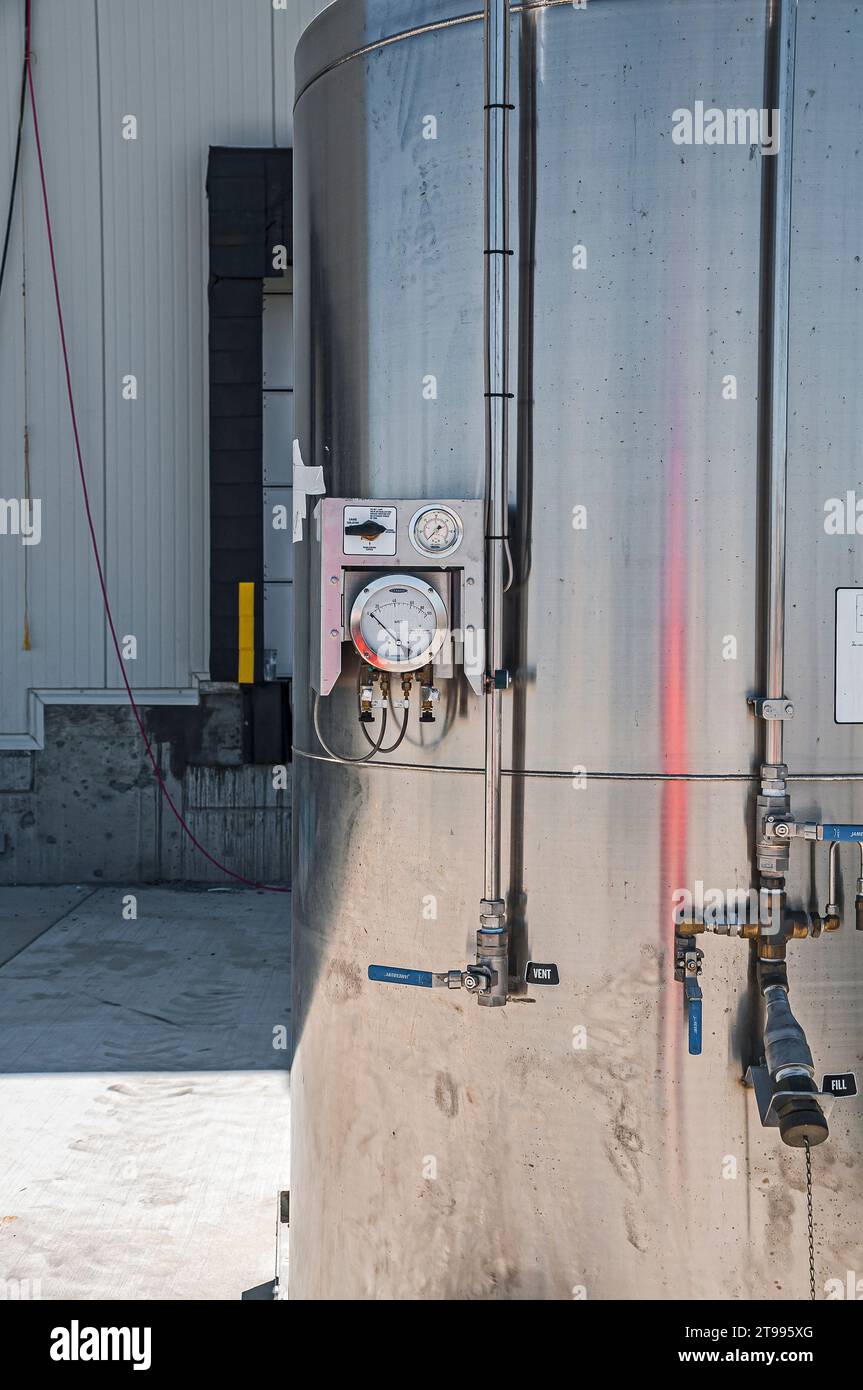 Detail view of a stainless-steel tank, outdoors on a metal pallet at an ...