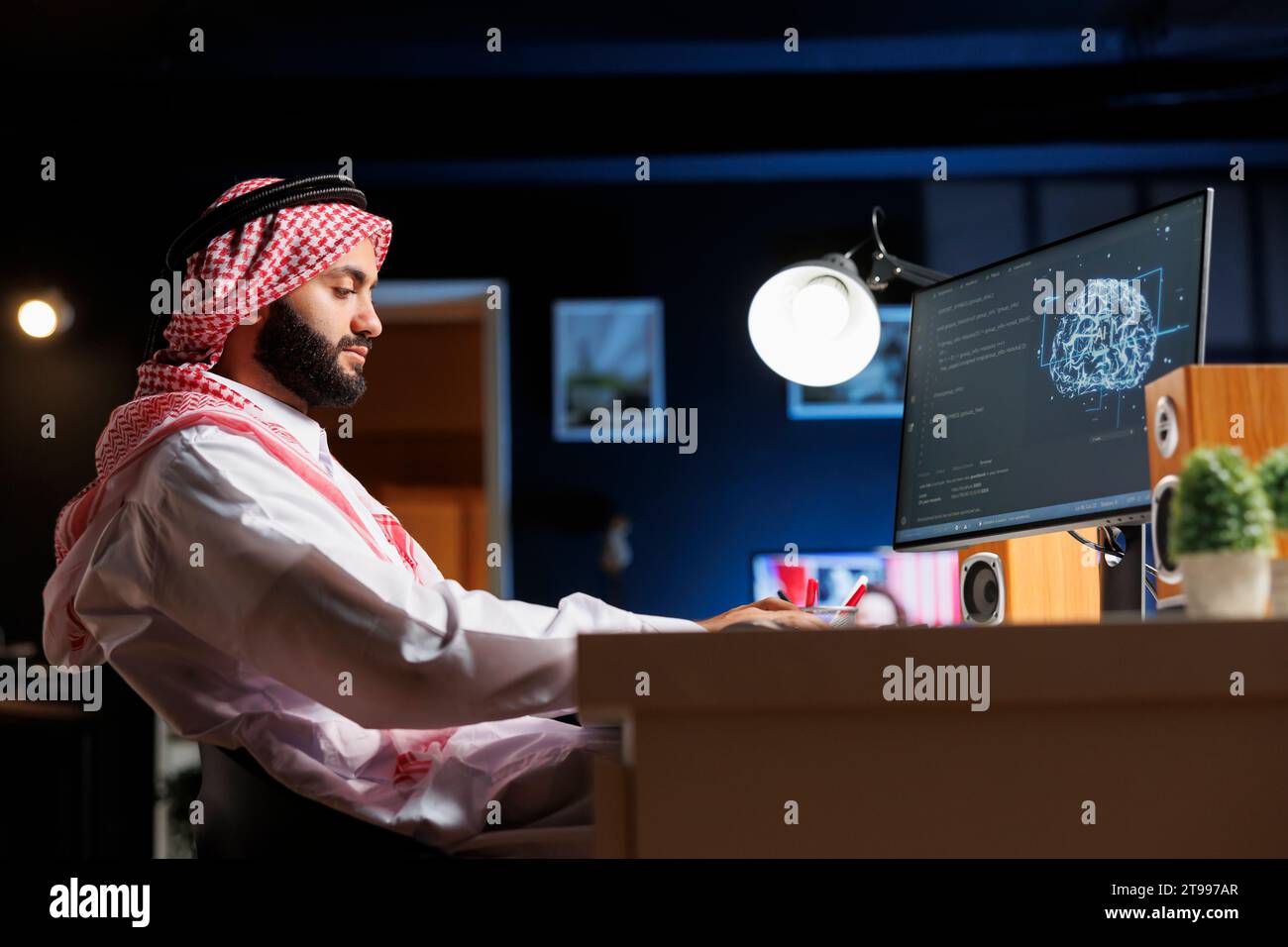 Side-view shot of a young man in Islamic attire analyzing code on a computer screen using AI and ...