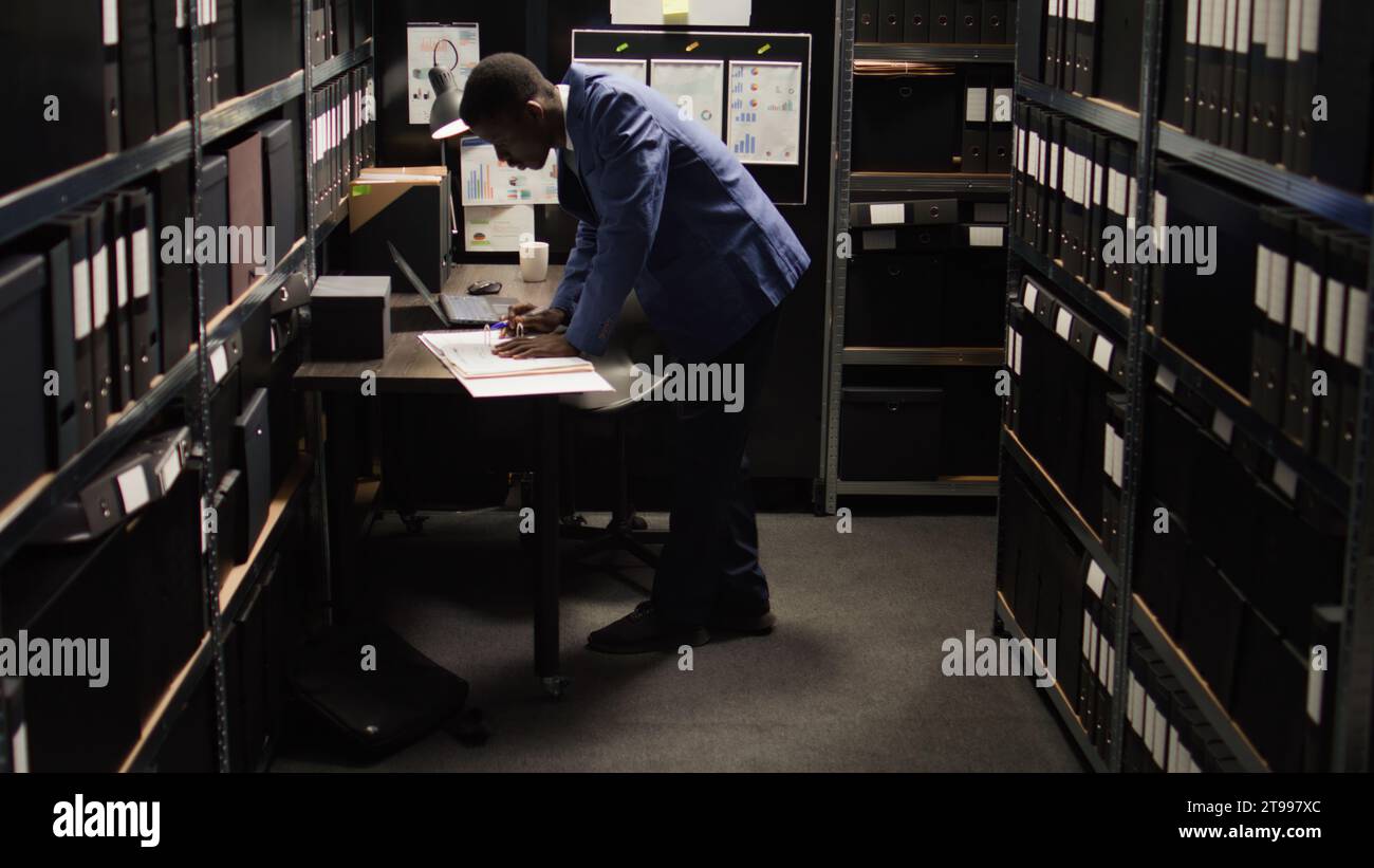African American policeman carefully analyzes material, does records ...