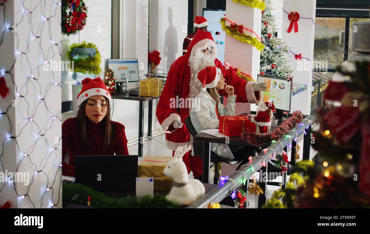 Manager dressed as Santa in xmas ornate office supervising tasks after ...