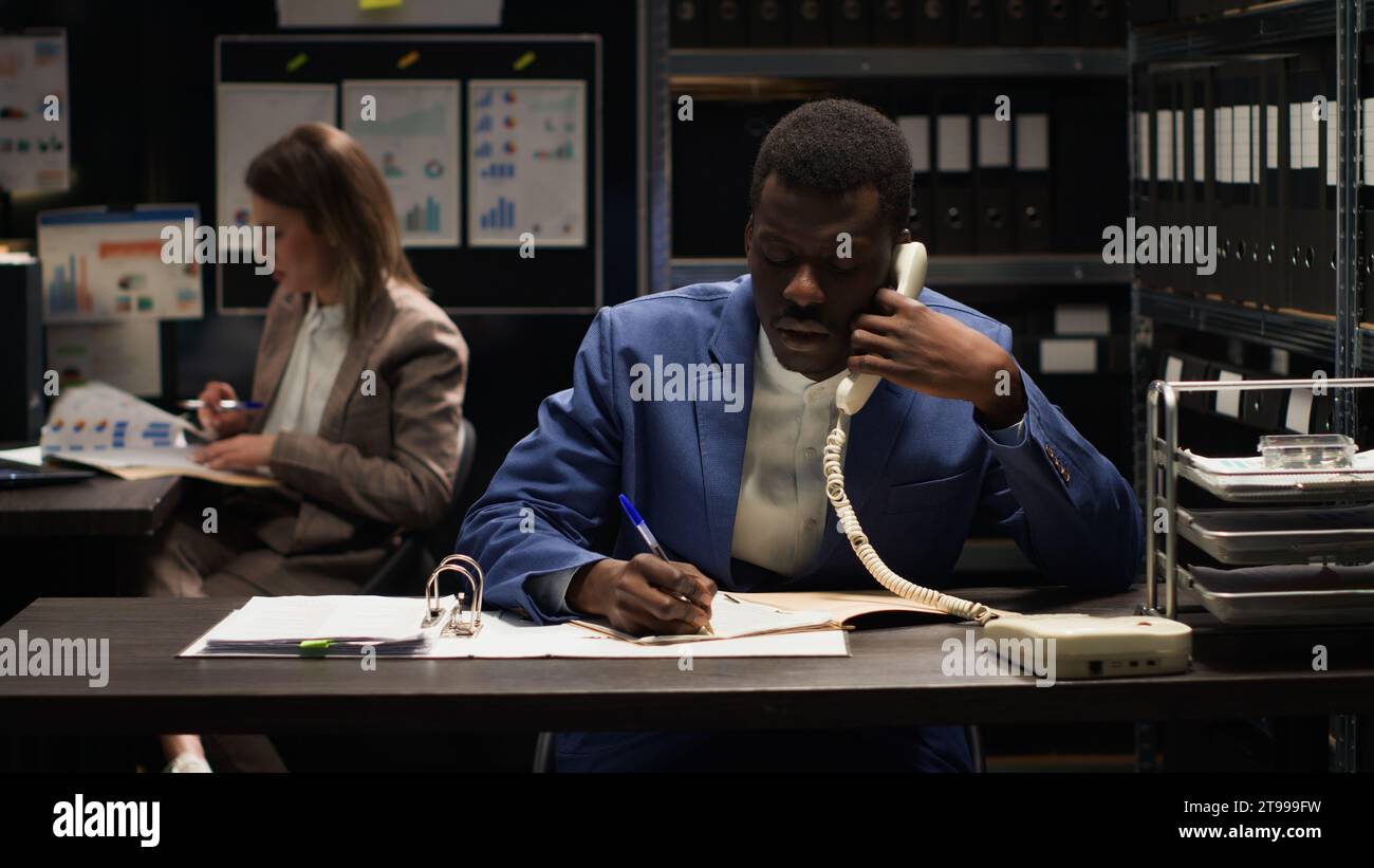 African American detective and Caucasian criminologist gather evidence ...