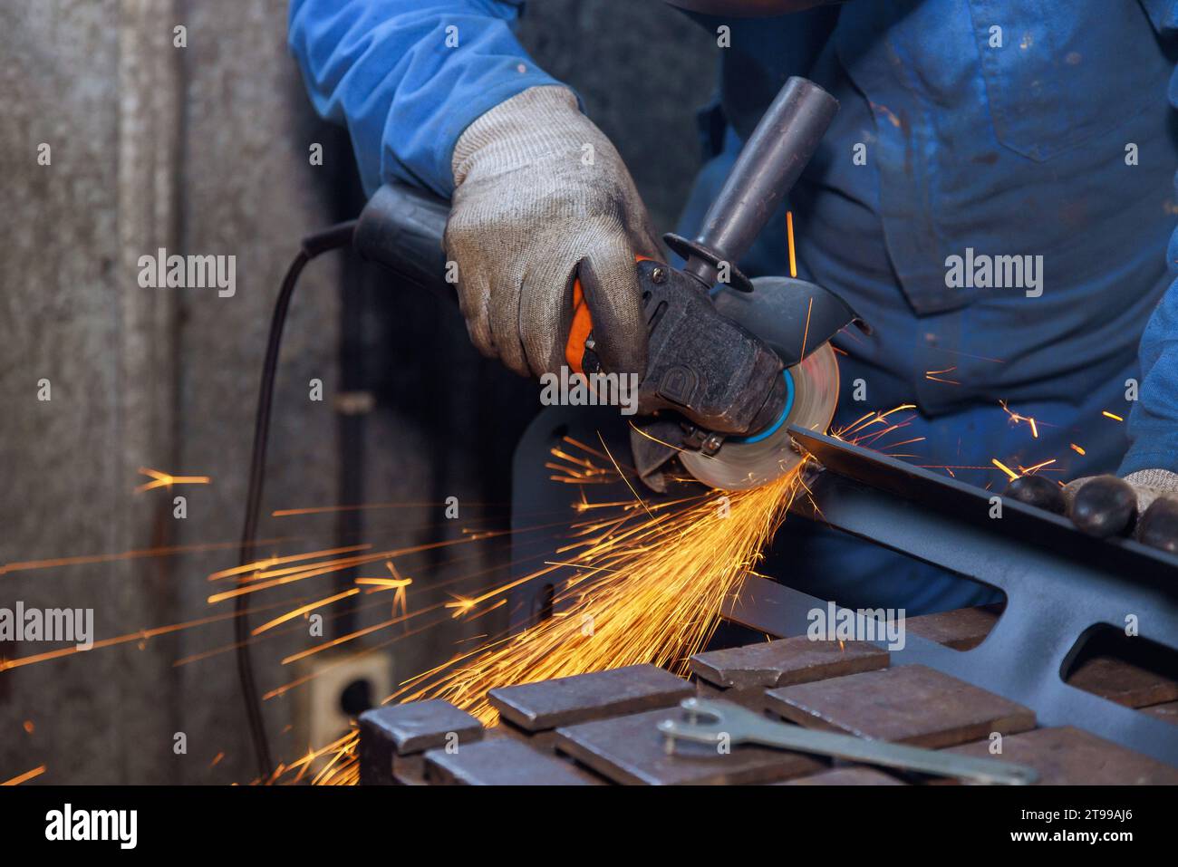 Worker cuts metal with an abrasive disk while grinding iron in ...