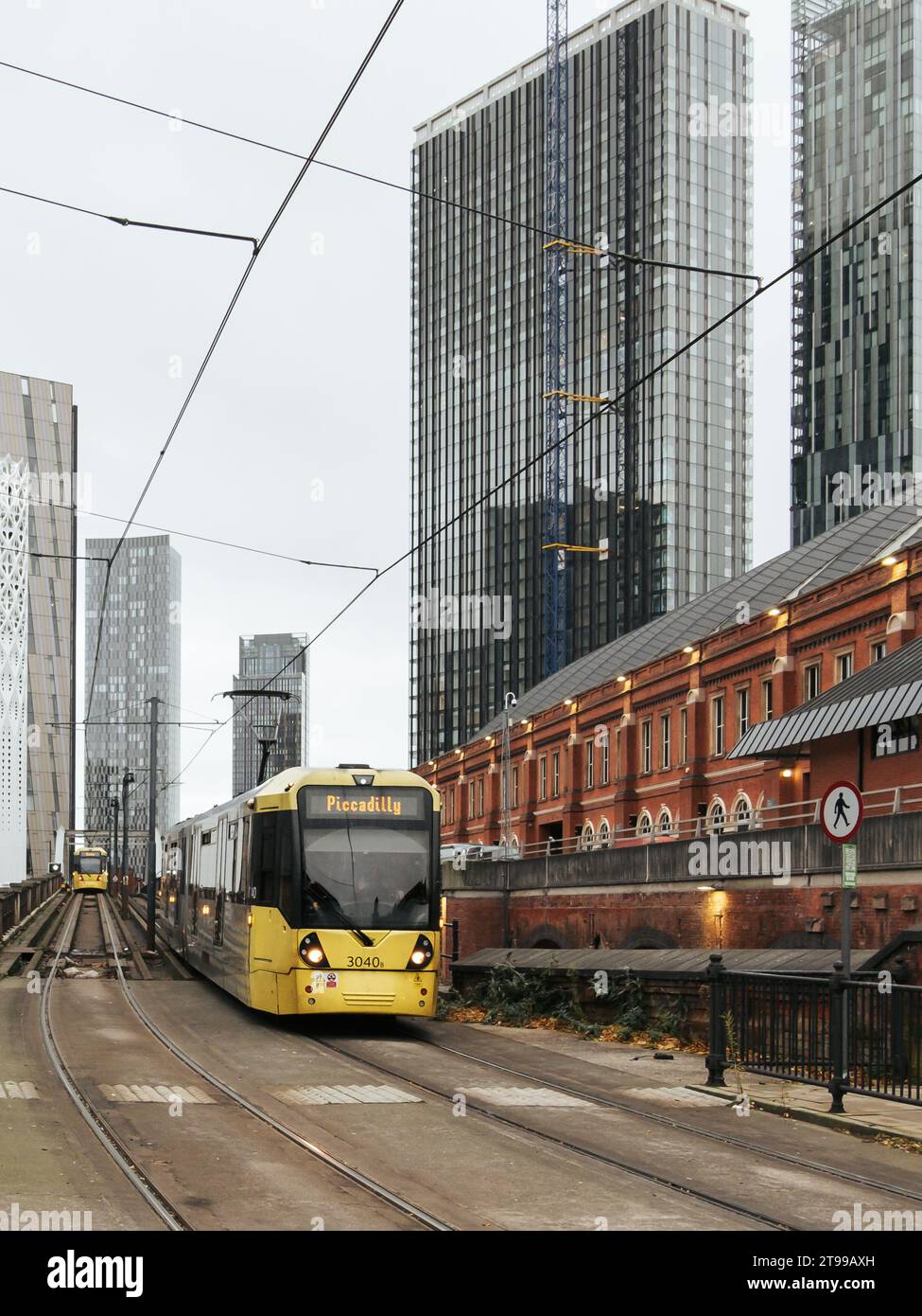 Manchester Bee Network Metrolink tram travels past the tall skyscrapers ...