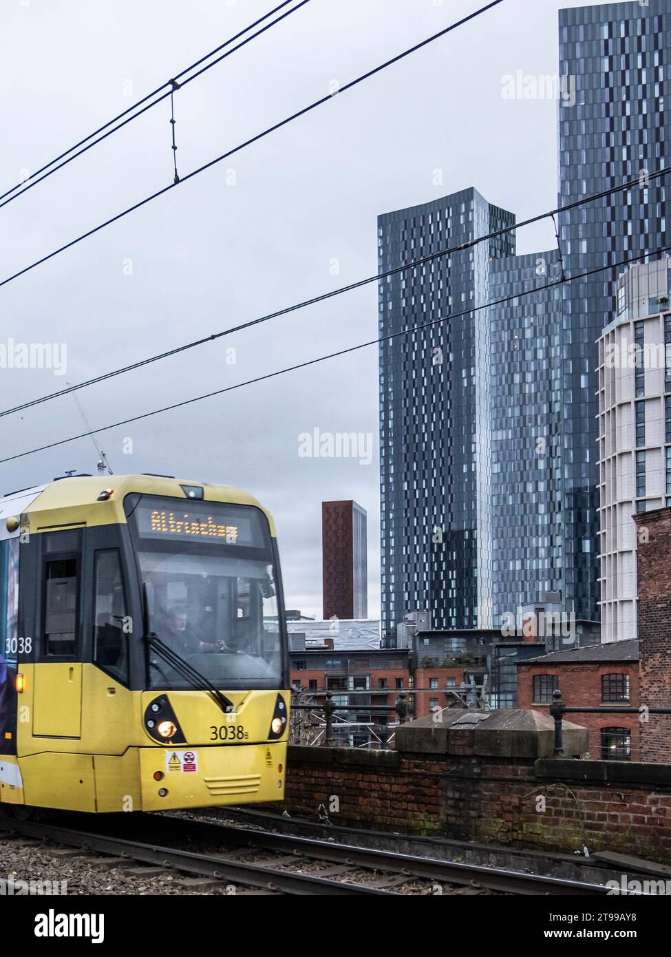 Manchester Bee Network Metrolink tram travels past the tall skyscrapers ...