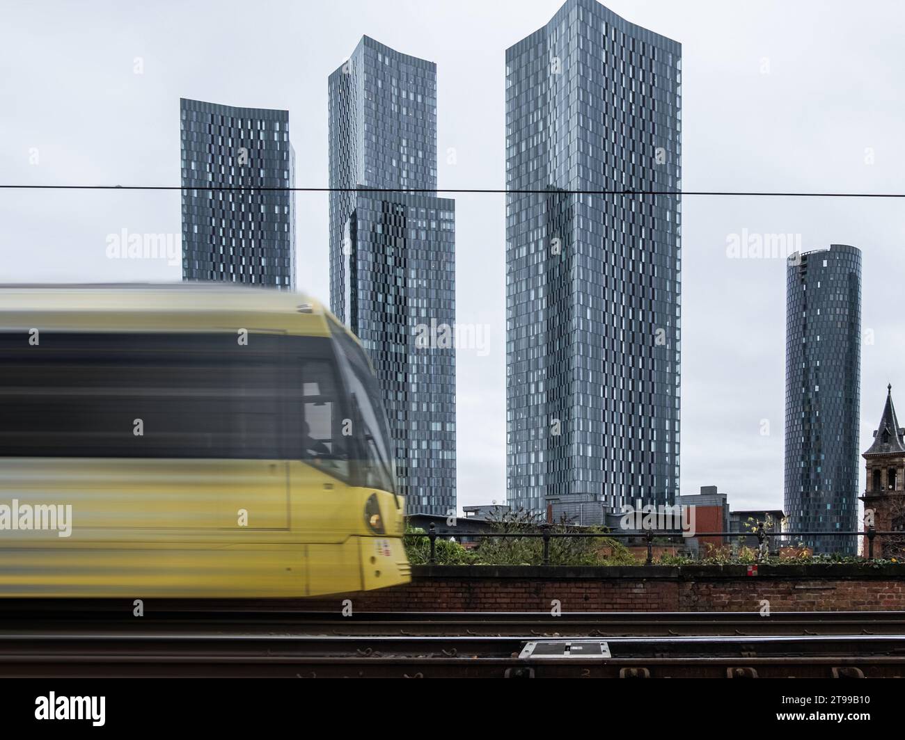 Manchester Bee Network Metrolink tram travels past the tall skyscrapers ...