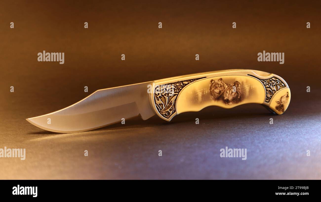 Folding hunting knife with wolves on the handle Stock Photo - Alamy
